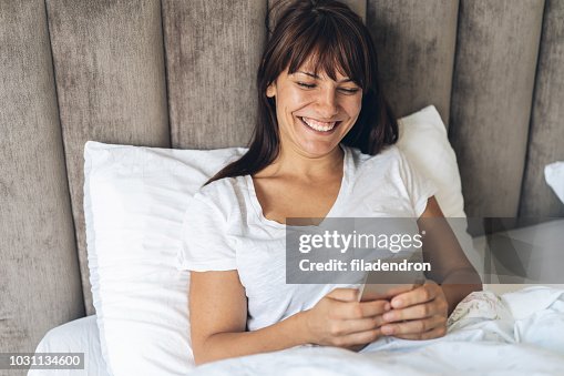 Femme Assise Dans Son Lit À Laide De Smartphone Photo Getty Images