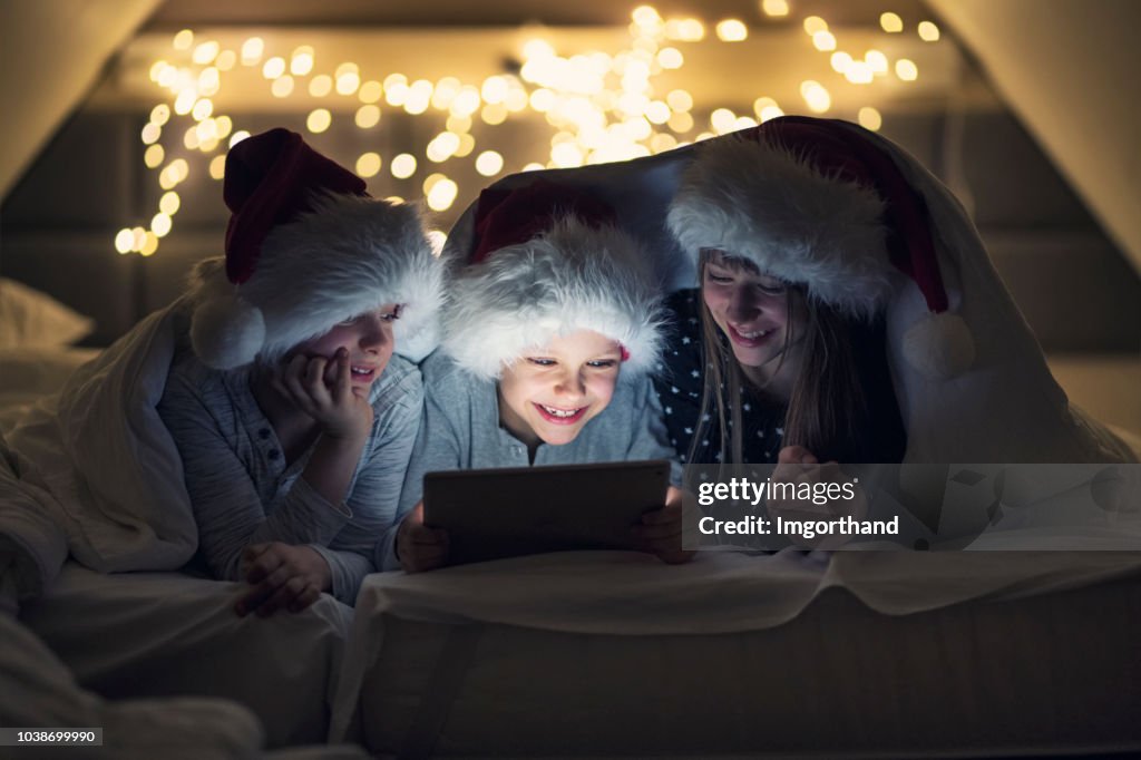 Brothers And Sister Reading Christmas Tales On Tablet High Res Stock