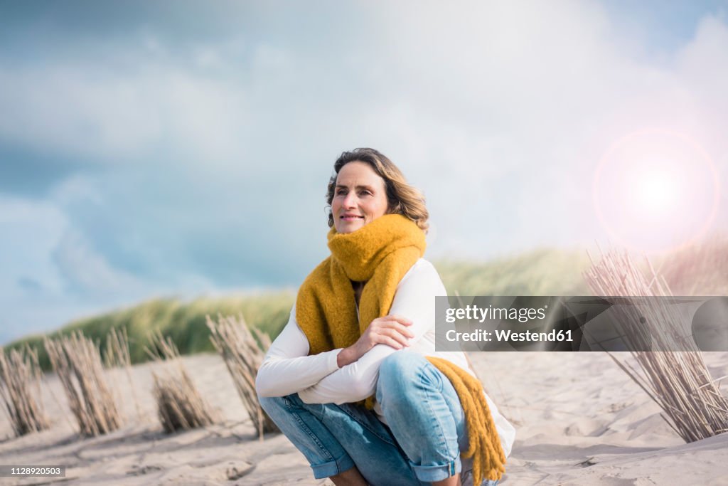 Mature Woman Crouching In The Dunes Enjoying The Wind Photo Getty Images