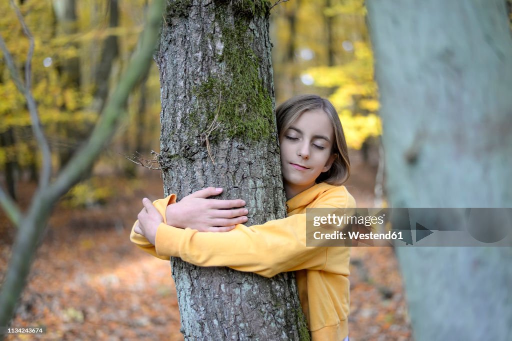 Portrait Of Girl With Eyes Closed Hugging Tree In Autumnal Forest High