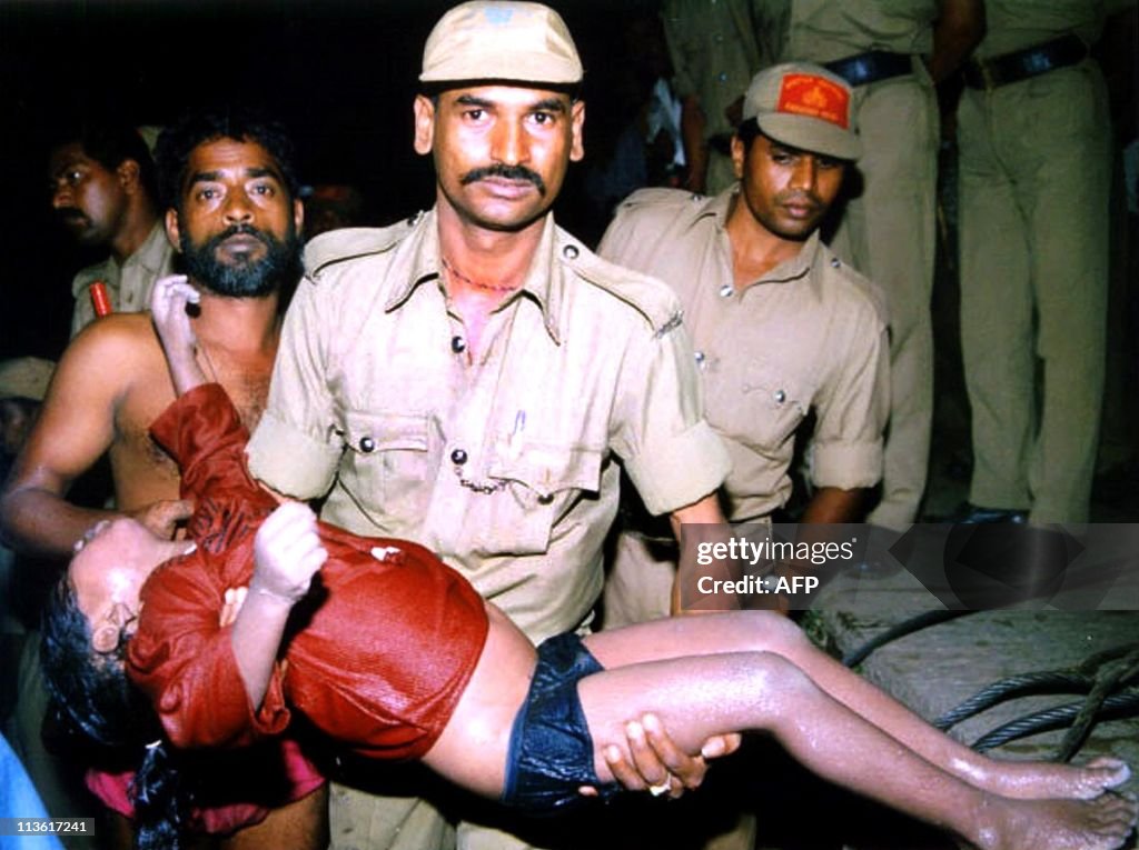 A Policeman Holds The Dead Body Of A Girl Whose Corpse Was Retrieved
