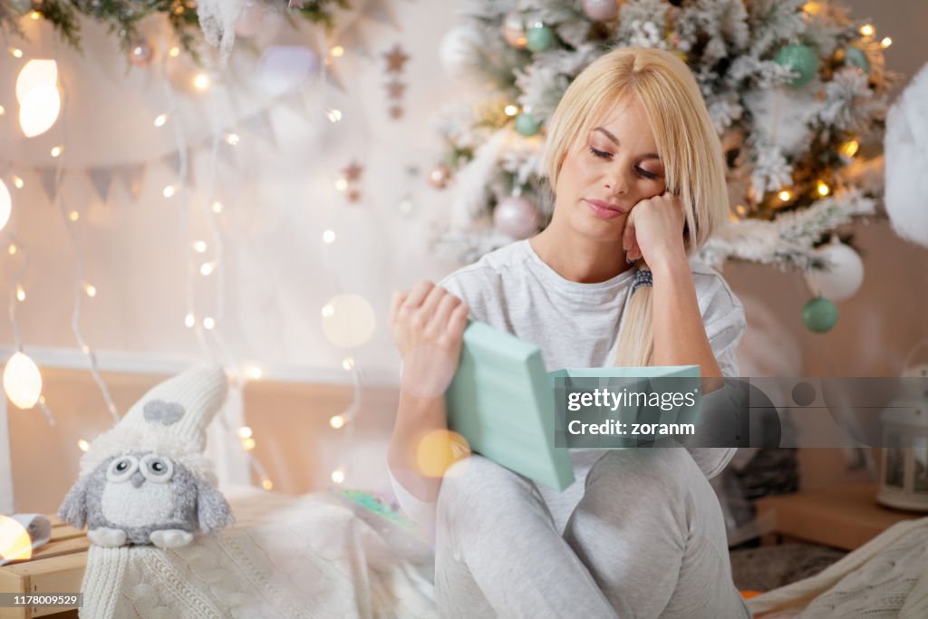 Woman Sitting By The Christmas Tree Disappointed With Her T High Res