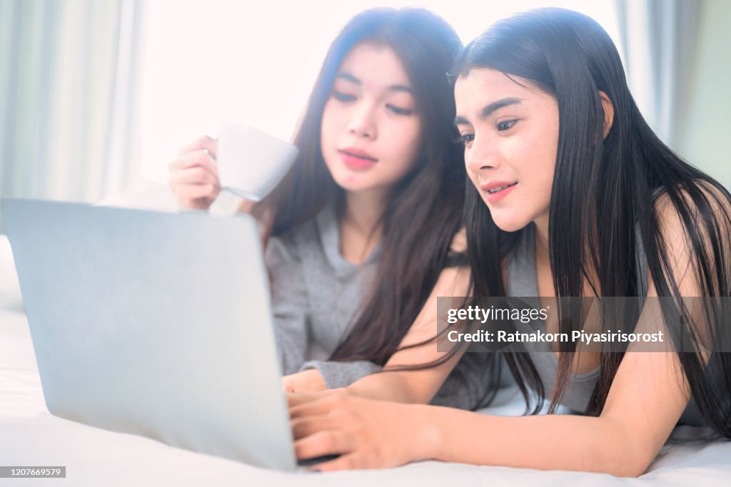 Asian Lesbian Lgbt Couple Lying On Bed Hug And Using Laptop Computer