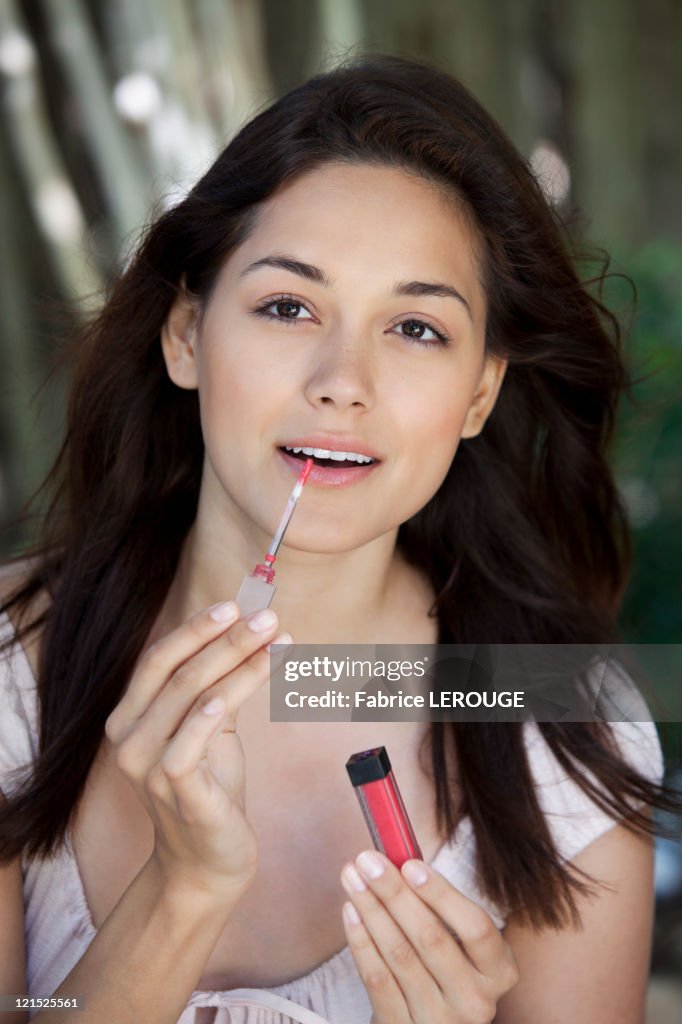Portrait Of A Beautiful Young Woman Applying Lip Gloss High Res Stock
