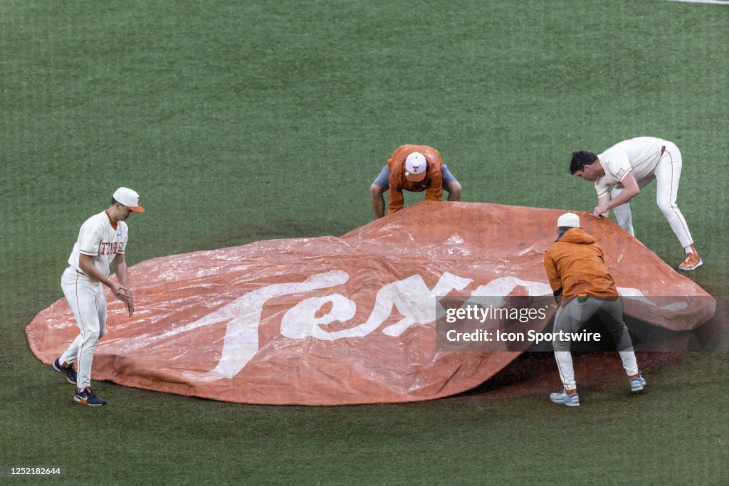 Texas Longhorns Players Pull The Tarp Over The Pitchers Mound During