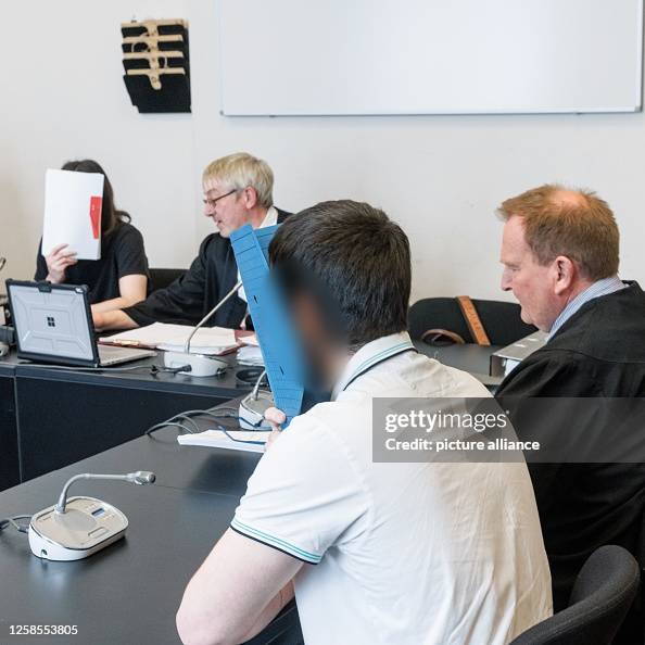 The two defendants hide their faces behind files in the courtroom ... The two defendants hide their faces behind files in the courtroom ...