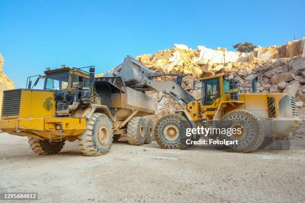 Big loader working in the marble quarry dumping pieces of marble rock ...
