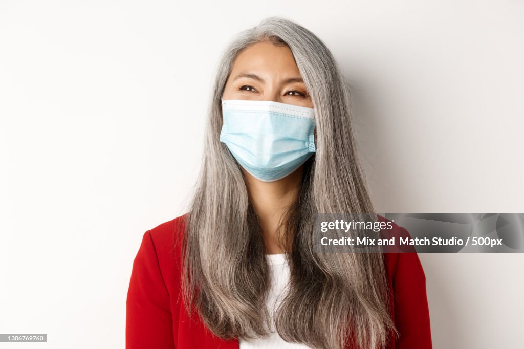 Portrait Of Woman Wearing Surgical Mask Against White Background High