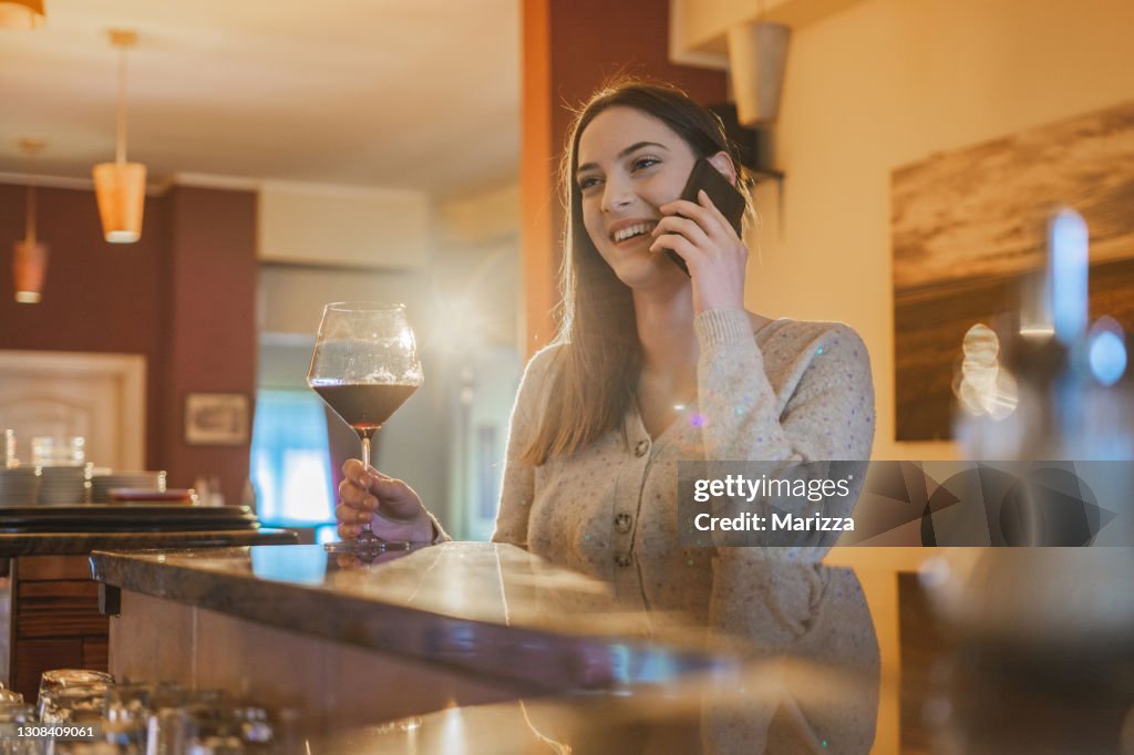 Cheerful Woman Laughing And Talking On Cell Phone In Bar High Res Stock