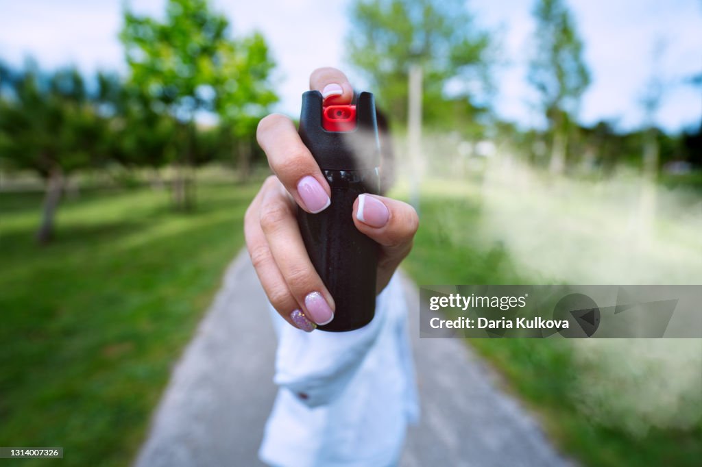 Woman Using Pepper Spray Or Tear Gas For Self Defence Outdoors High Res