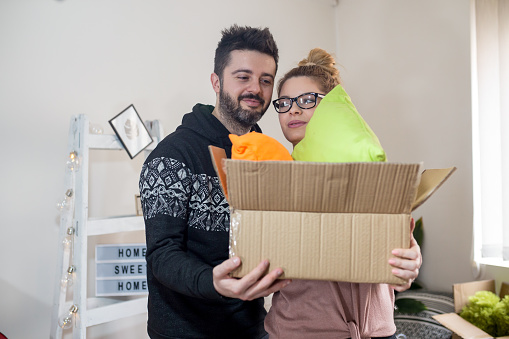 Beautiful Young Couple Holding Cardboard Boxes While Moving To New Home