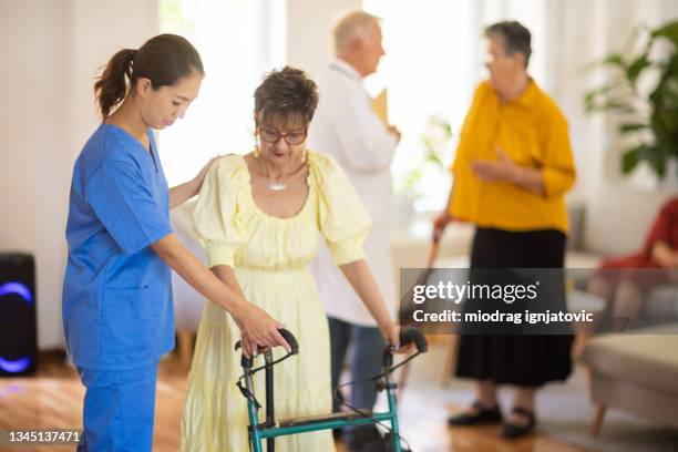 Nursing Assistant Helping Senior Man With Walking Frame Photos And