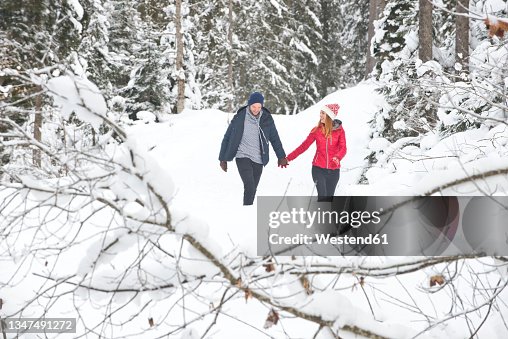 Couple Holding Hands While Walking On Snow During Winter High Res Stock