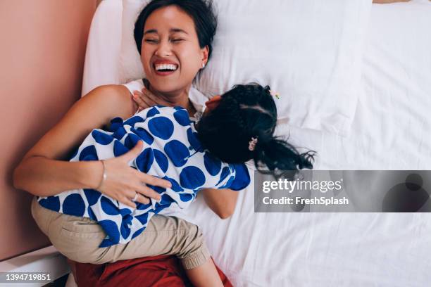 61 Overhead View Smiling Mother And Daughter Hugging On Bed Stock