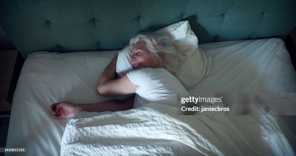 Mature Woman Relaxing In Comfortable Bed Smiling And Feeling Cozy High