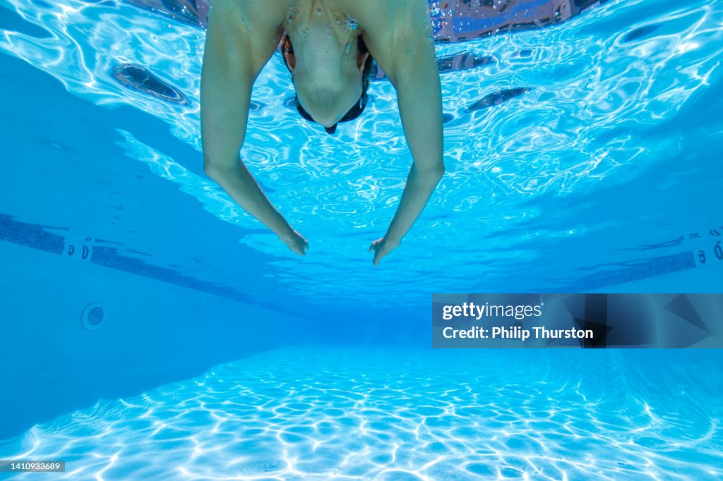 Young Woman Swimming Freely Underwater In An Outdoor Pool On A Sunny