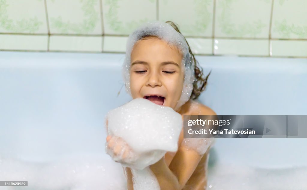 Playful Girl Playing With Soap Sud While Taking Bath In Bathroom High