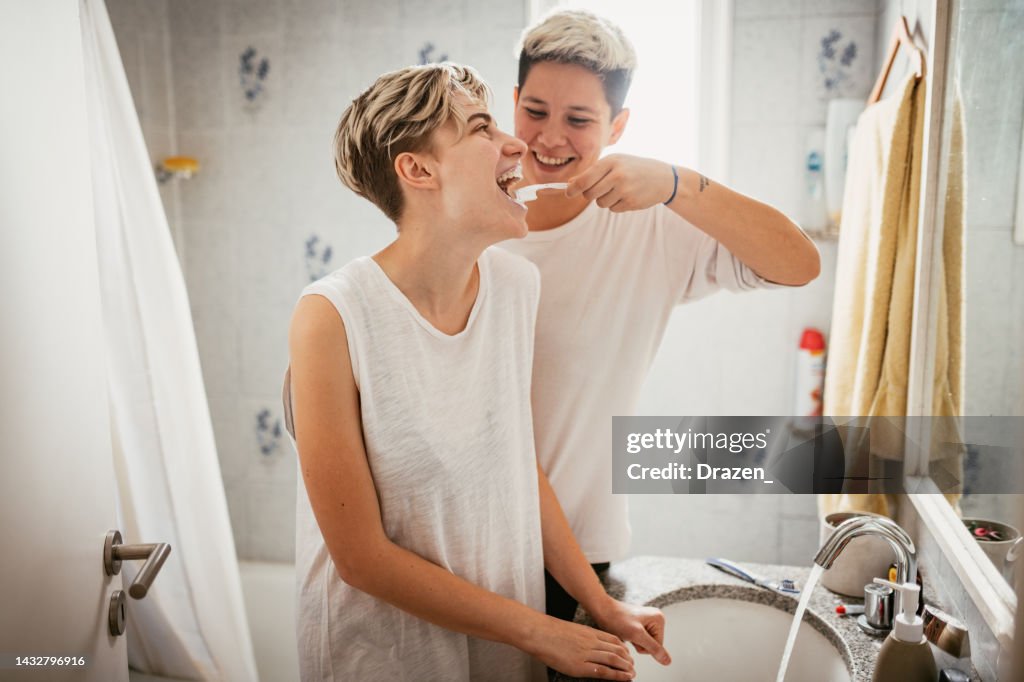 Millennial Lesbian Couple Brushing Teeth And Washing Face In Bathroom