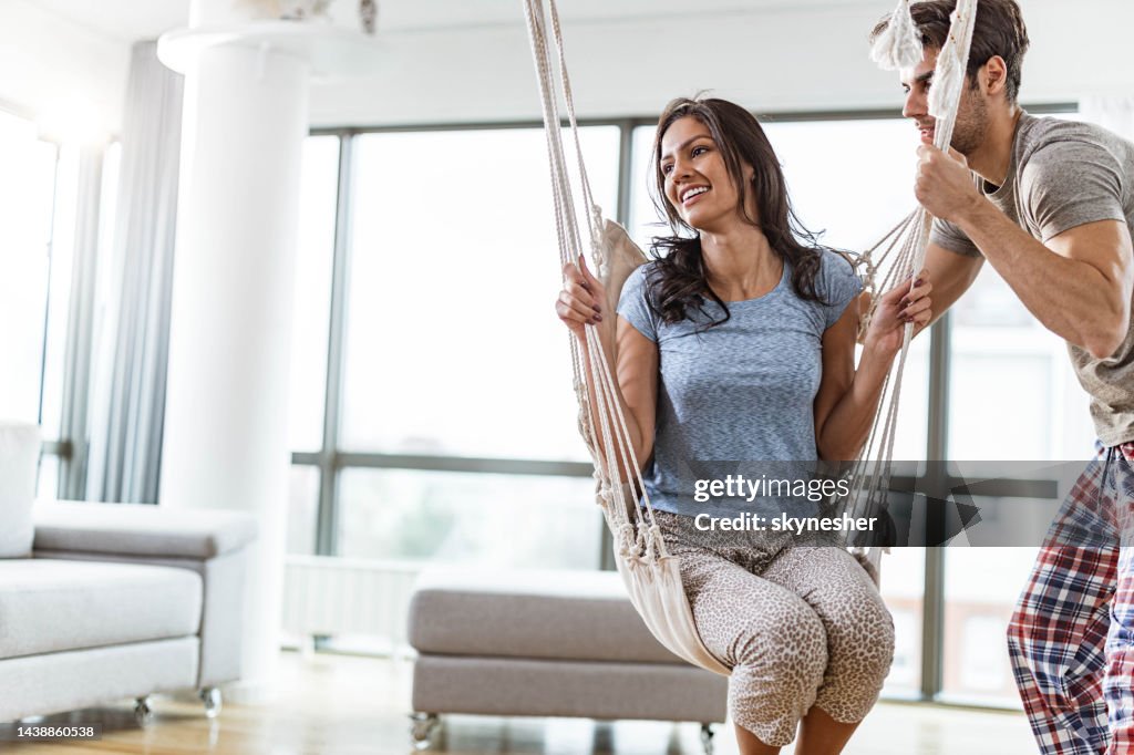 Young Man Having Fun While Swinging His Girlfriend At Home High Res