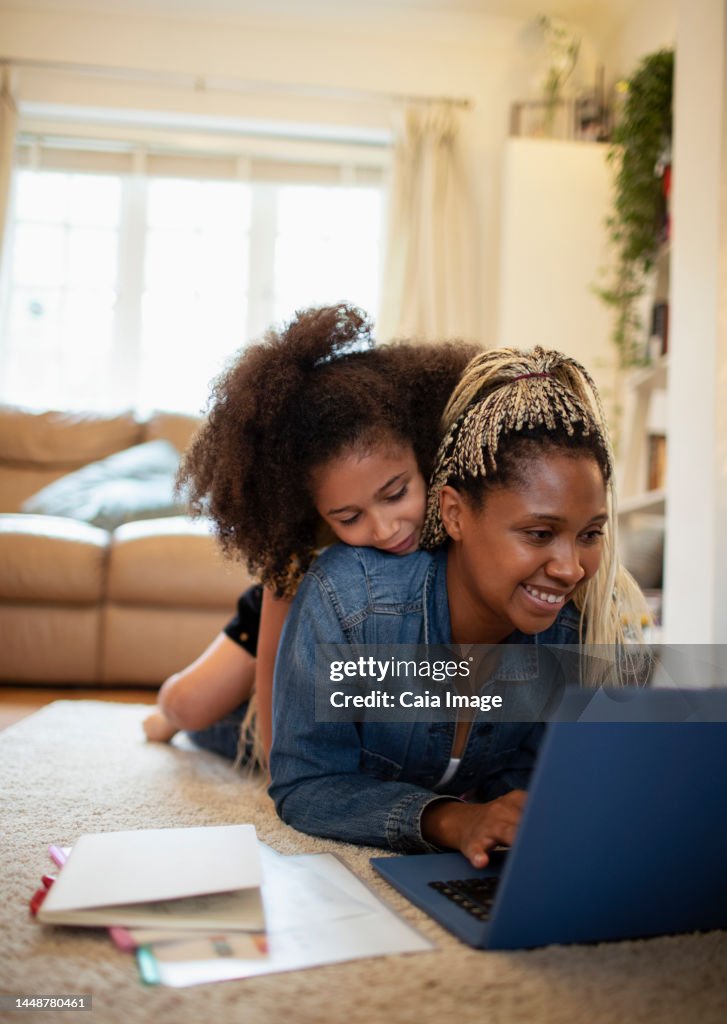 Curious Girl Watching Mother Work At Laptop On Living Room Floor High