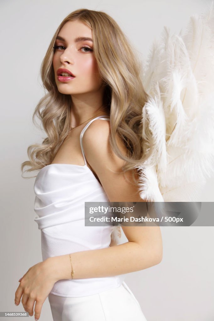 Portrait Of Beautiful Young Woman Wearing White Dress Against White