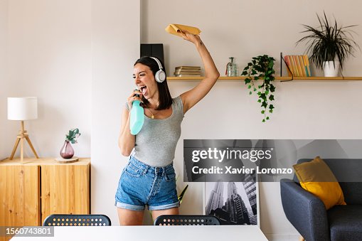 Excited Young Adult Woman Singing And Dancing While Cleaning The House