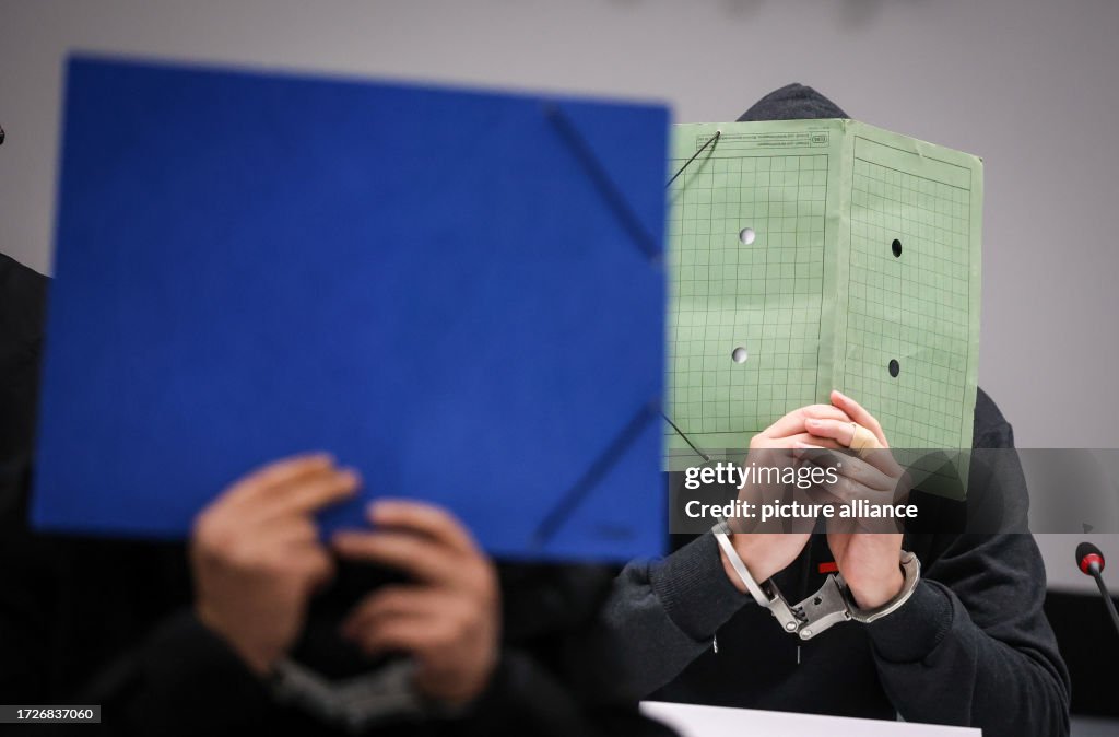 Two defendants hold folders in front of their faces in the external ... Two defendants hold folders in front of their faces in the external ...