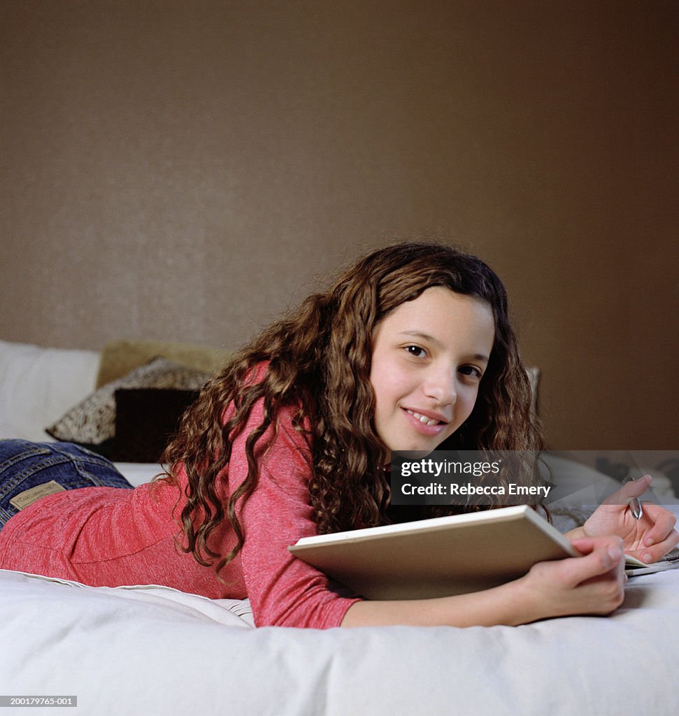 Girl Lying On Bed Writing In Notebook Smiling Portrait High Res Stock