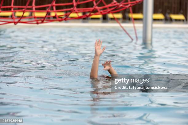 Hands of drowning person stretching out of the water in swimming pool ...