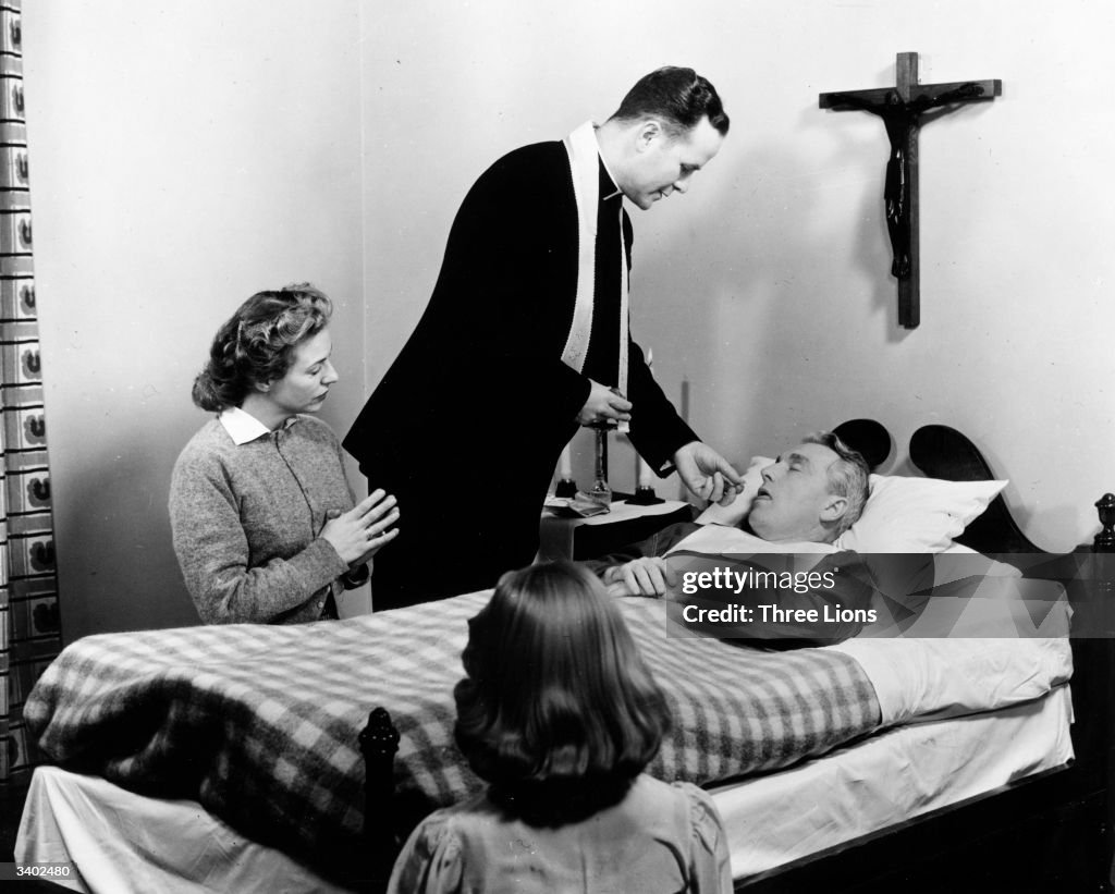 A Catholic Priest Administers The Host To A Dying Man During The