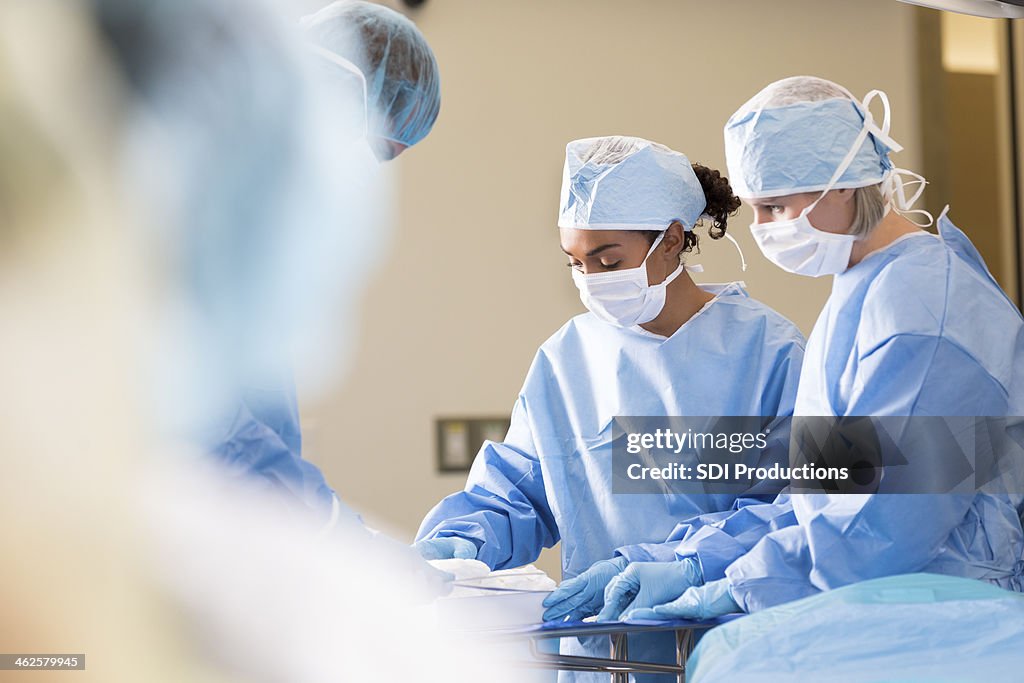 Surgeons Preparing Surgical Instruments For Procedure In Operating Room