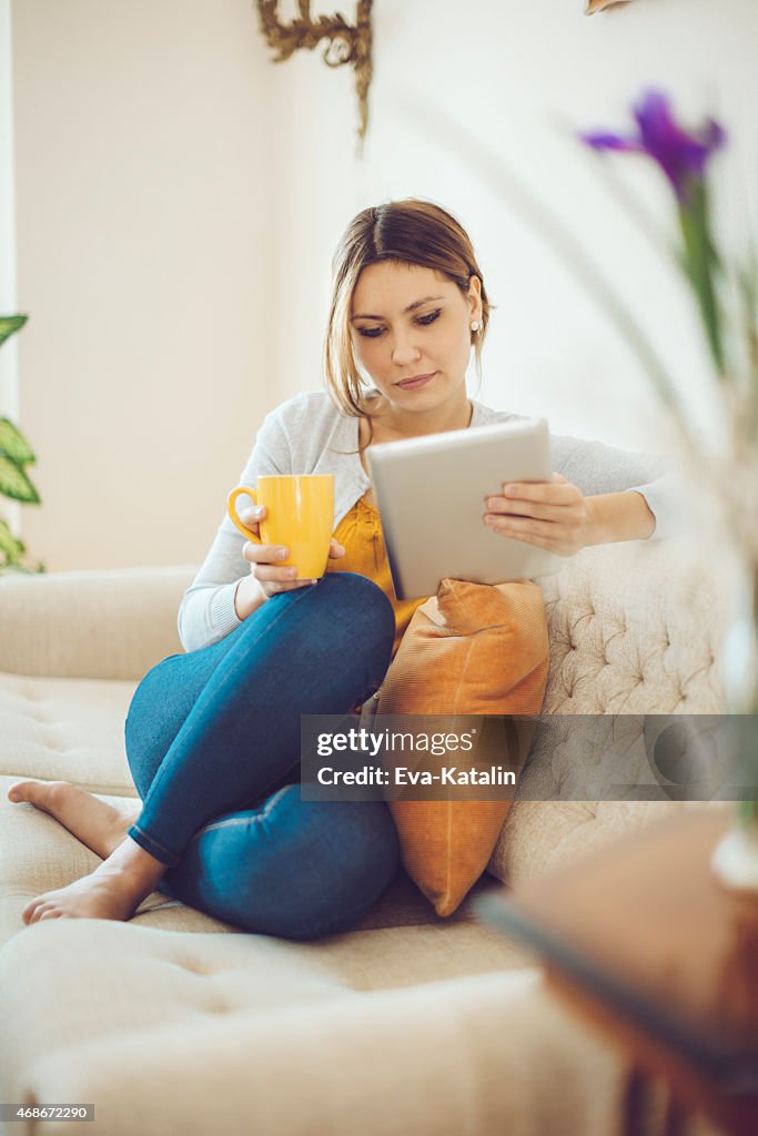 Confident Woman Drinking Coffee And Reading A Tablet High Res Stock