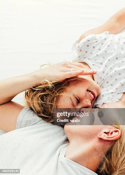 60 Overhead View Smiling Mother And Daughter Hugging On Bed Stock