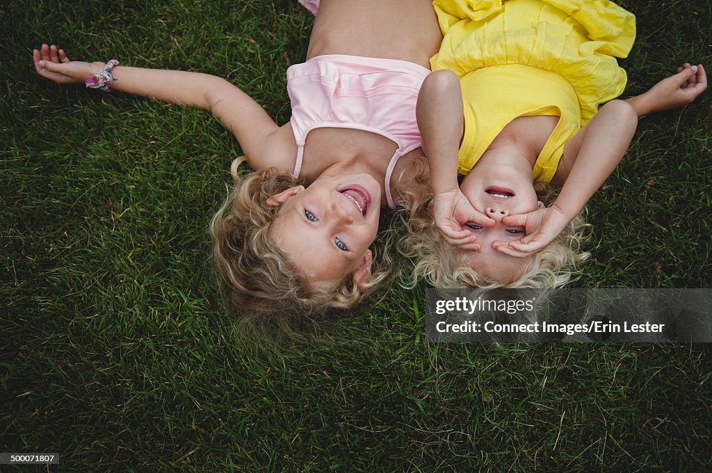 Portrait Of Two Young Sisters Lying Upside Down On Grass High Res Stock