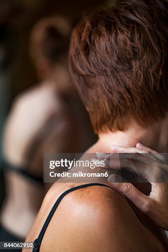 Woman Looking In Mirror To See Sunburned Skin On Shoulder That Peeling