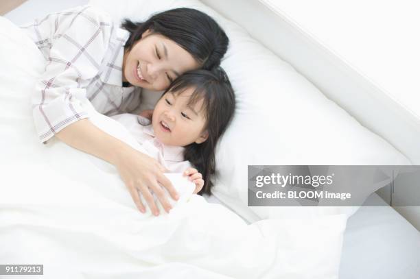 60 Overhead View Smiling Mother And Daughter Hugging On Bed Stock