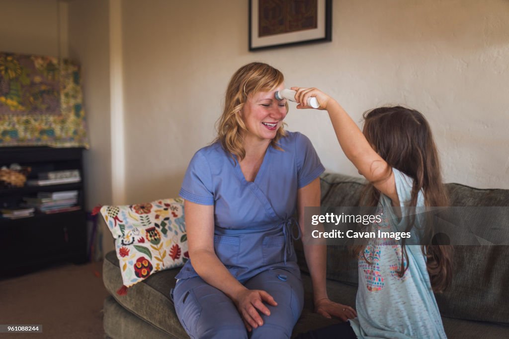 Girl Giving Head Massage To Female Doctor While Sitting On Sofa At Home