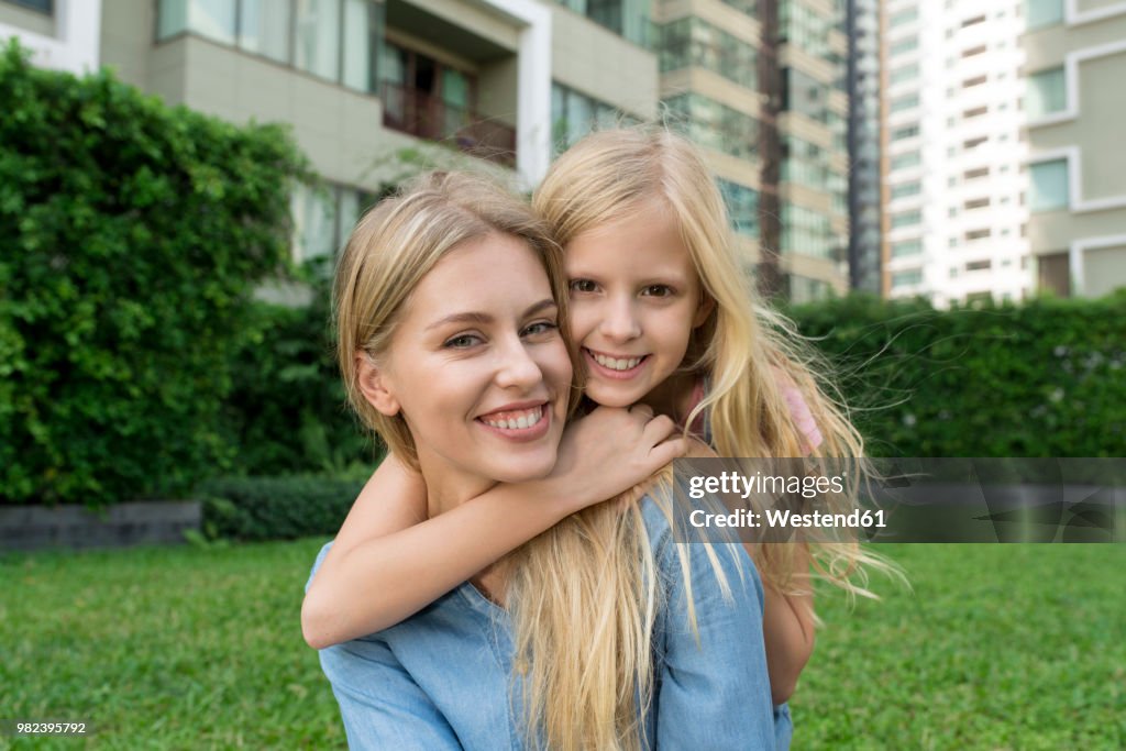 Happy Mother And Daughter Hugging And Smiling In Urban City Garden High