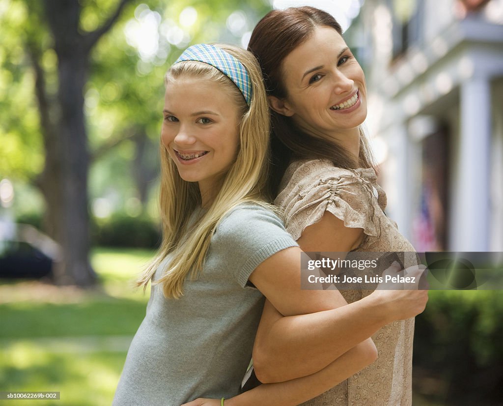 Mother And Daughter Standing Back To Back Smiling Portrait High Res