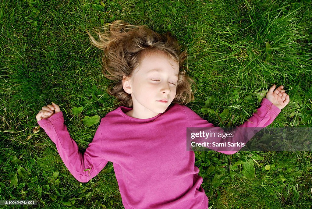 Girl Lying Down In Grass With Eyes Closed Overhead View High Res Stock